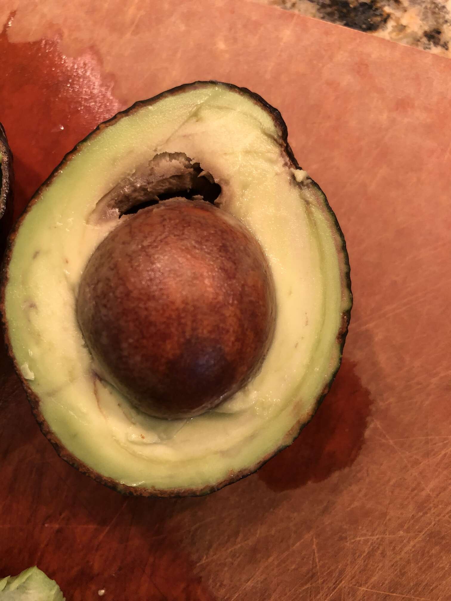 Avocado with a dark spot and hole near the pit